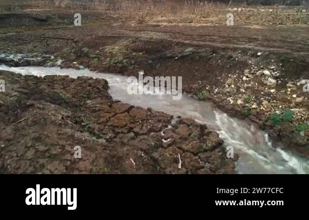 A stream flowing through the field in early spring. Shot. Aerial view ...
