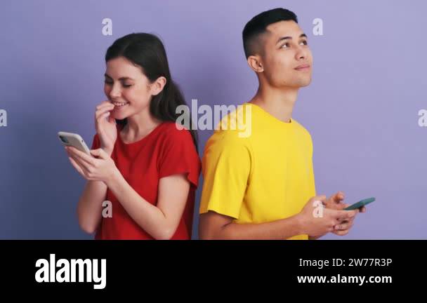 The couple in love texting on the phone while standing back to back in ...