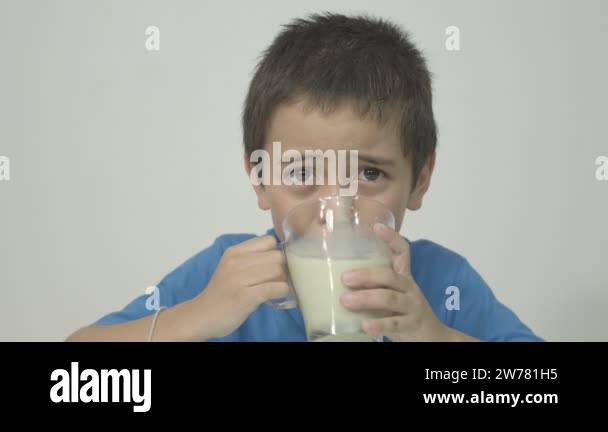 The cute boy wearing a blue shirt tasted the milk to know the taste and ...