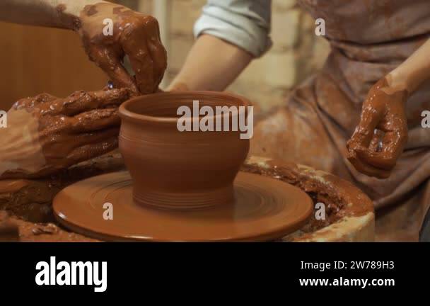 Teaching pottery A craftsman hands guiding a woman hand, showing how to ...