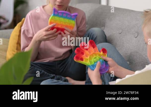 Kids playing with pop it sensory toy. boy and girl pressing on colorful ...
