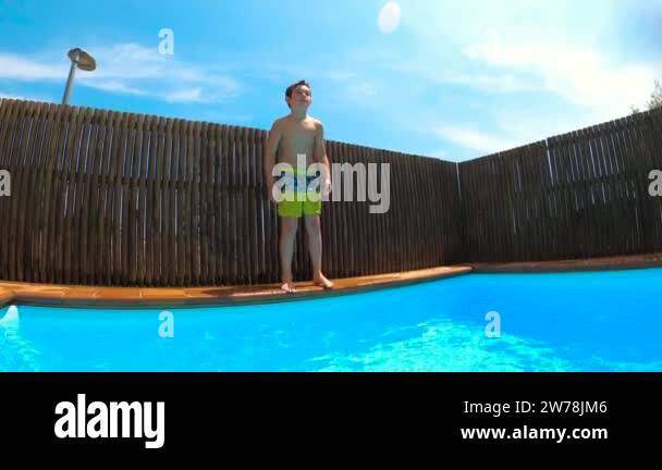 SLOW MOTION, UNDERWATER, SUN FLARE: Caucasian Boy jumping head first ...