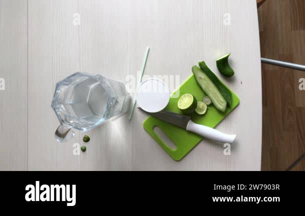 The man puts the straw in a glass with sliced lime and cucumber ...