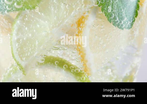 Macro refreshing soda tonic fizzy sparkling water, lime in glass, ice cubes. Slice of lemon ...