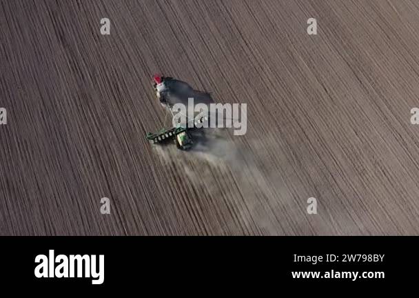 Aerial view of tractor with harrow system plowing ground on cultivated ...