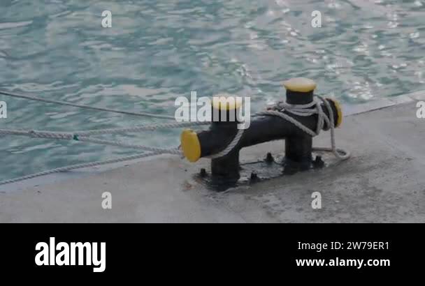 Shoreside bitts with mooring ropes. Paired vertical metal posts mounted ...