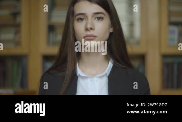 Female student, library. Girl looks straight in the camera and smiles ...