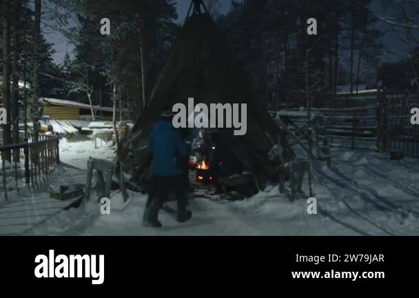 A young man enters the wigwam tent in a rural courtyard where a group ...