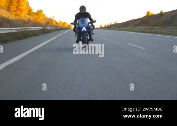 Front view of young man in helmet riding fast on modern sport motorbike ...