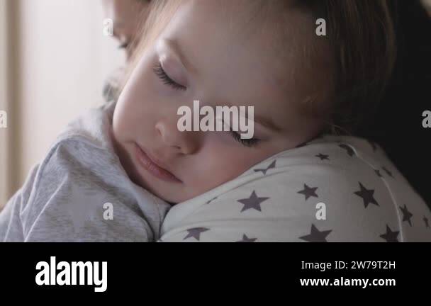 Baby, child sleeps in her mothers arms. A loving young mother embraces ...