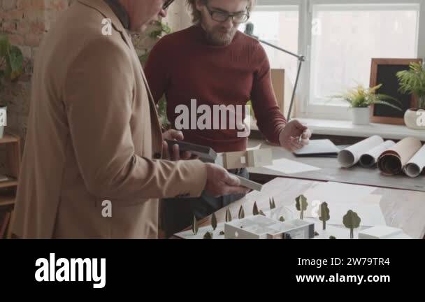 Tilt-down slowmo of professional male architects creating 3d layout of ...
