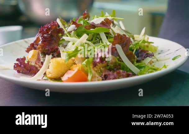 Close-Up.Cooking salad. A Female Chef in a Black Uniform Sprinkles ...