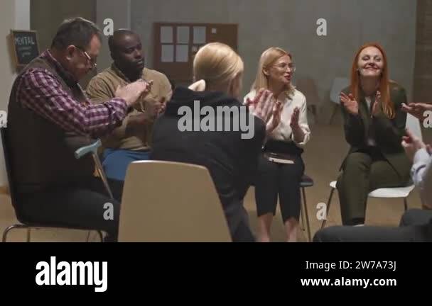 PAN shot of smiling people of different age and nationality sitting in ...