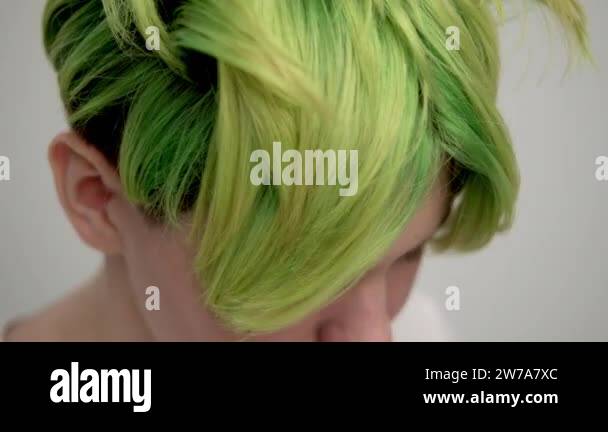 A young girl with a short pixie haircut and green hair in a white T ...