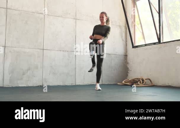 A strong woman with leg prosthesis is doing sport exercises while ...