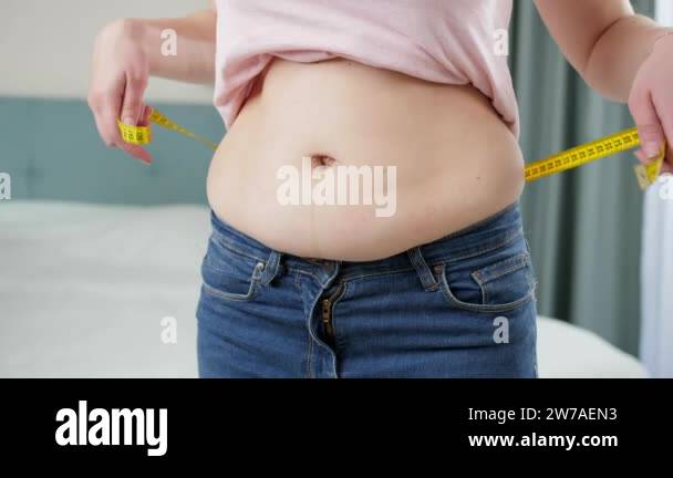 Young obese woman struggling to measure big belly with measuring tape ...