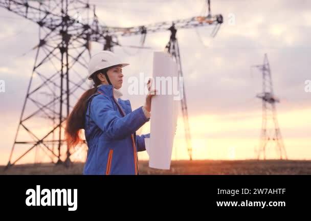 An electrician on the background of high towers of power plants looks ...