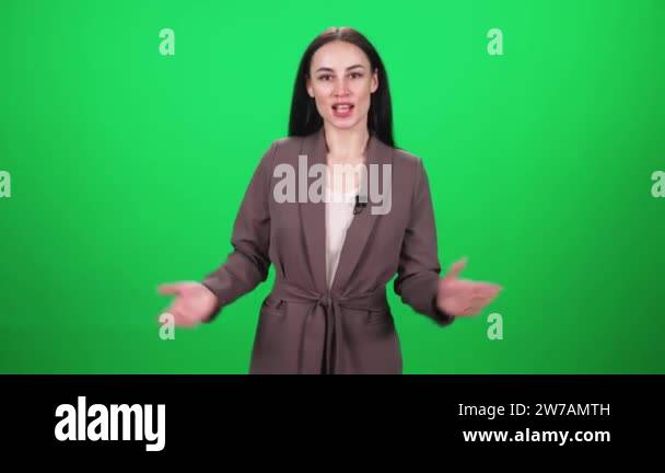 Female reporter in suit looks into the camera and speaks into a ...