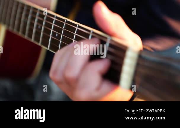 Man plays a guitar and sings outdoor songs at sunset. Hand on the ...