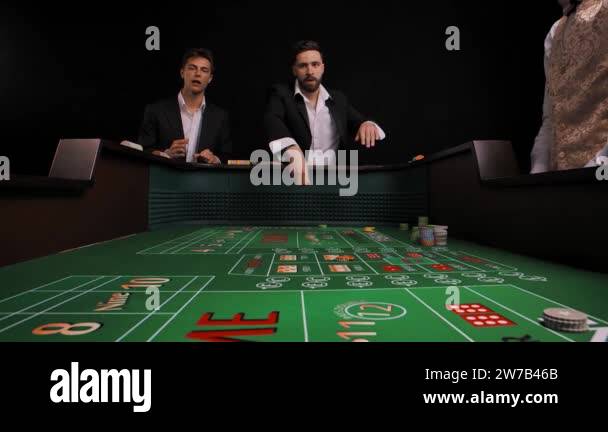 Two men in business suits stand at a green craps table in a casino. The ...