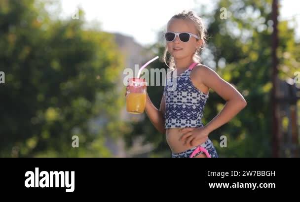 Beautiful little girl, cute toddler with sunglasses is drinking orange ...
