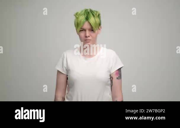 A young girl with a short pixie haircut and green hair in a white T ...