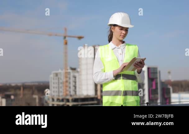 Portrait of young woman engineer who is working on the tablet. Her hair ...
