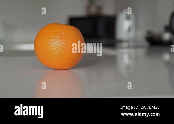 Horizontal pan to the left footage of one single orange on the white ...