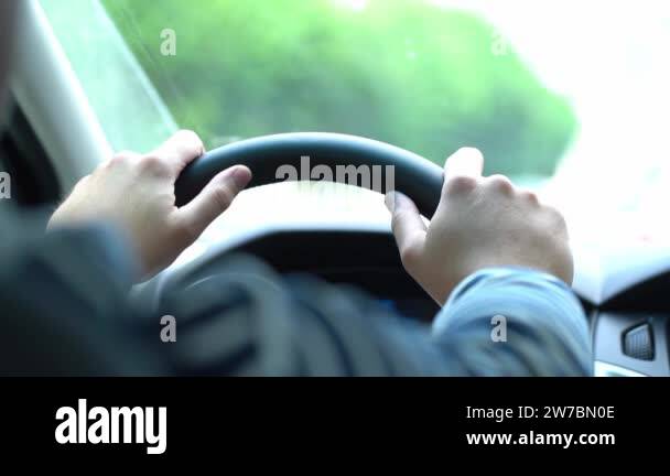 Driver behind the wheel of the car, hands wrap around the steering ...
