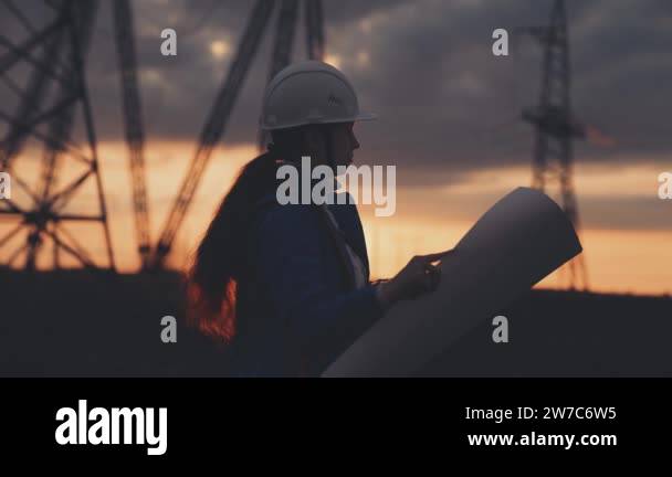 An electrician on the background of high towers of power plants looks ...