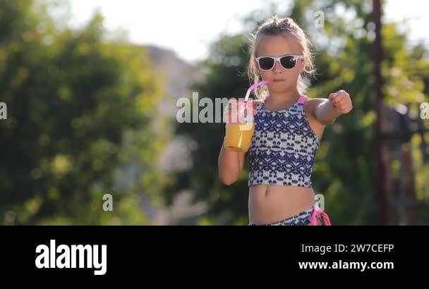 Beautiful little girl, cute toddler with sunglasses is drinking orange ...