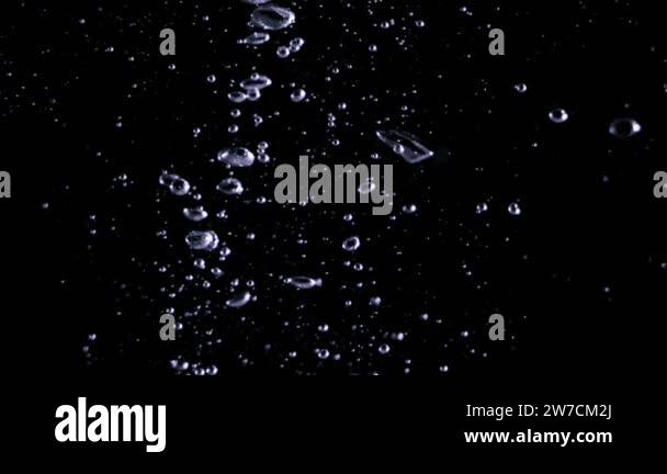 Soda water bubbles splashing underwater and floating water drop in black background. Motion ...
