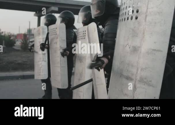 Tilt up slowmo shot of unrecognizable riot police officers in full gear ...