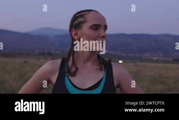 Fit and active young woman taking a break from jogging on early morning ...