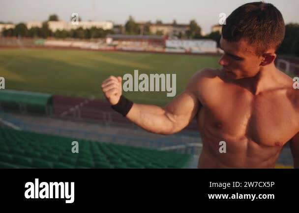 A bodybuilder stands on the podium of the city stadium and demonstrates ...