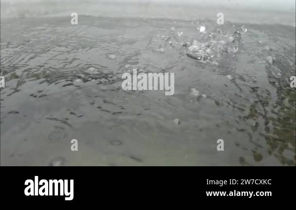 Rain water drops falling into big puddle on asphalt, flooding the ...