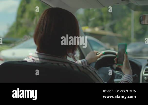 30s woman driving car in the city traffic jam and talking online using ...