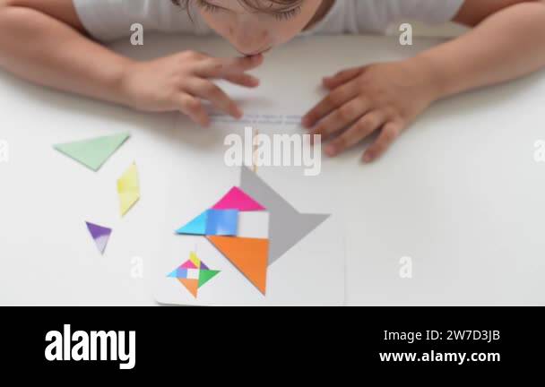 A preschooler girl sitting at the table collects a drawing from a ...