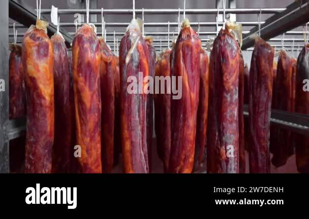 Cured meat hang from a rack at meat processing plant. Traditional food ...