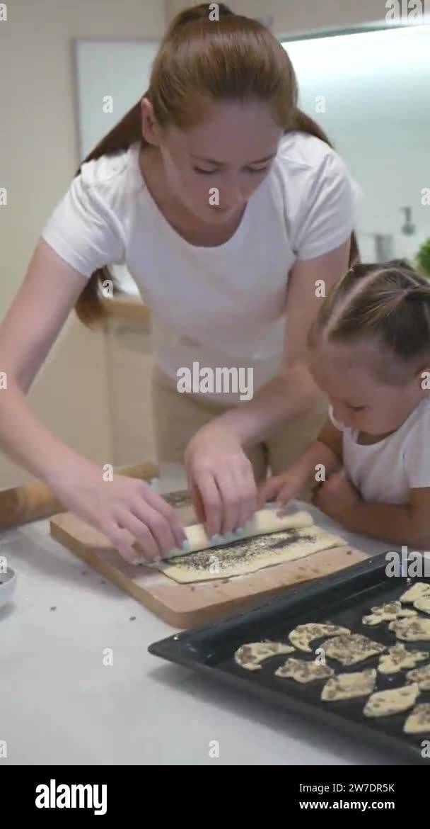 Cute toddler girl and mother roll up puff pastry with poppy seeds. Cute ...