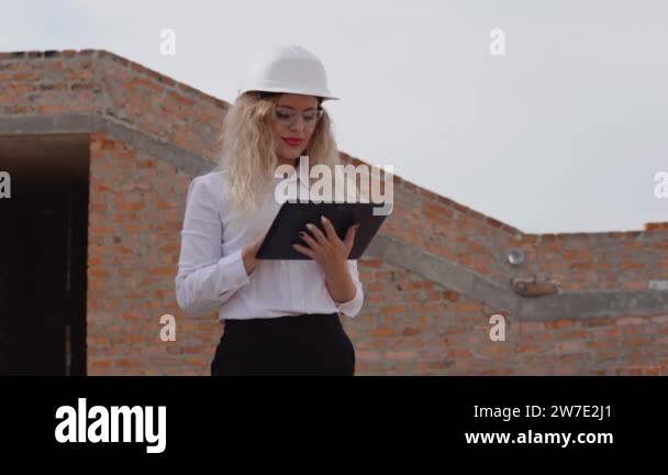 Female architect in business attire stands in a newly built house with ...