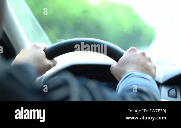 Driver behind the wheel of the car, hands tightly grip the steering ...