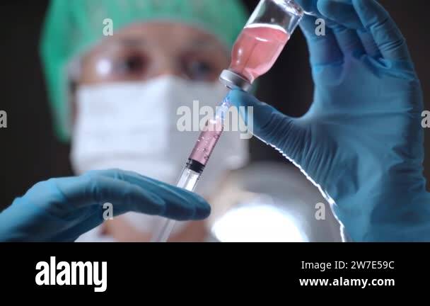 Medical scientific researcher infusing red solution in sterile vial ...