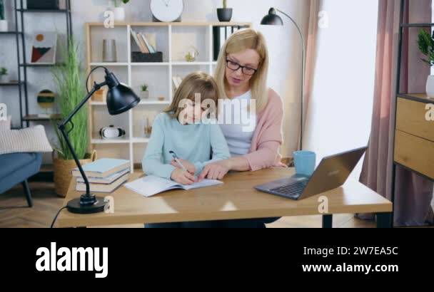 Attractive happy smiling light-haired mother in glasses helping her ...