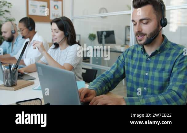 Handsome man call center agent talking to client using laptop then ...