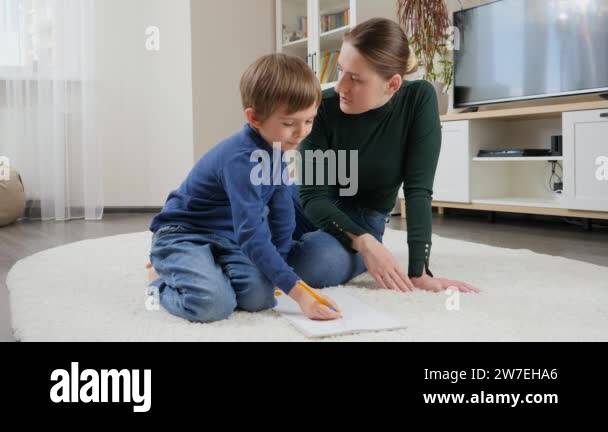 Young Mother Scolding And Shouting At Her Son Doing Homework On Floor