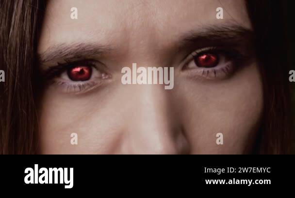 A girl with red vampire eyes, looking into the camera and in the eyes ...