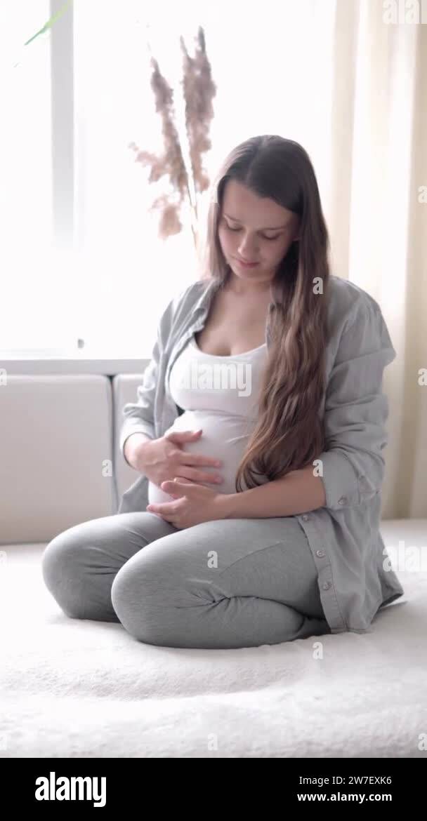 Vertical Format Video Of Happy Pregnant Woman Touching Tummy In Bed At