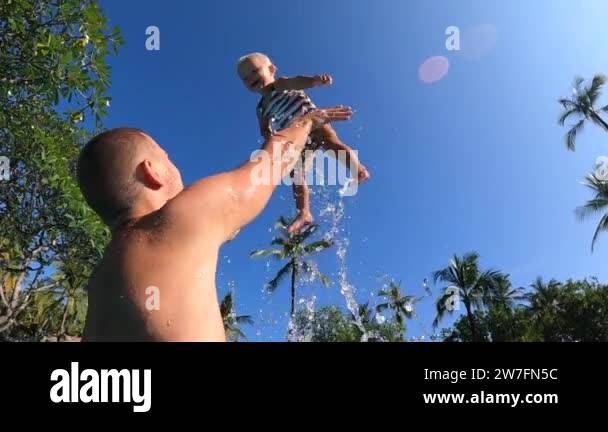 Shot from the bottom on a baby girl being thrown up in the air by her ...