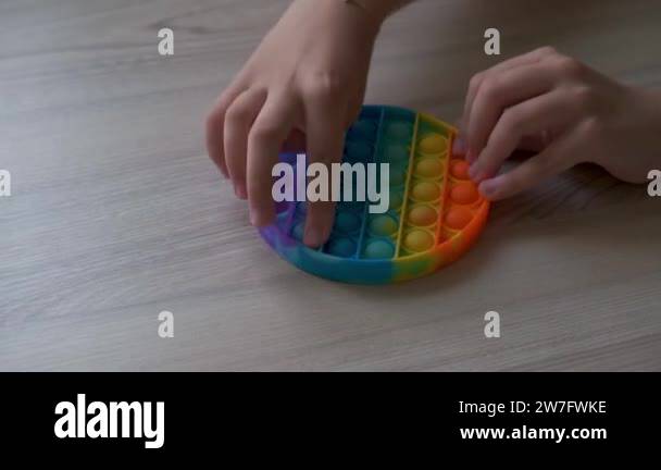 Close up shot of kids fingers on pop it fidget toy. Instrument for ...